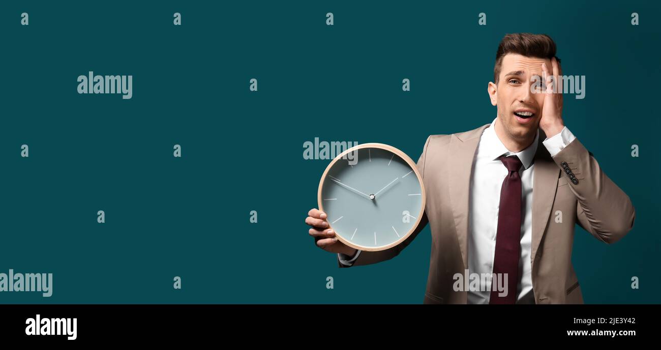 Stressed young businessman holding clock on color background with space for text. Time ...