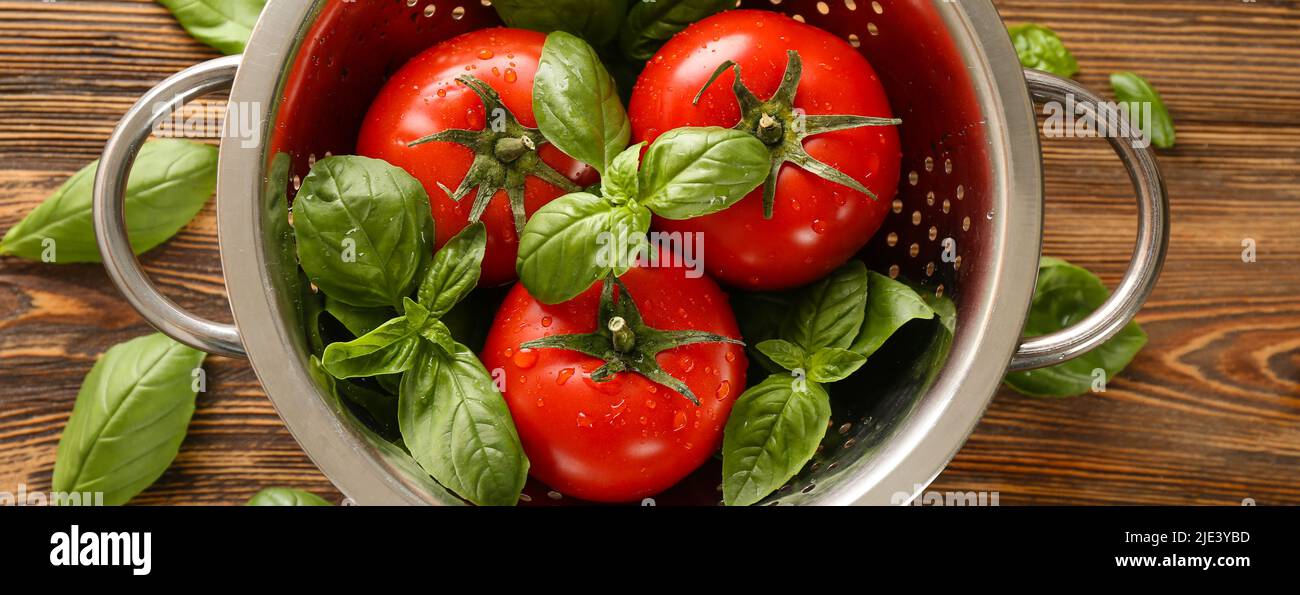 Colander with fresh basil and tomatoes on wooden background, top view ...