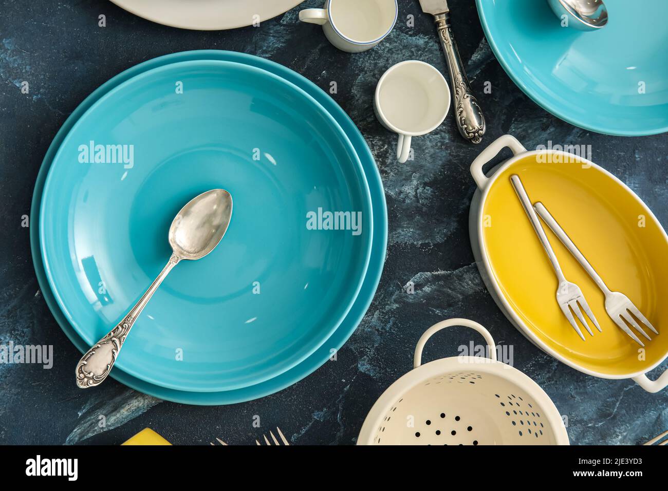 Colorful dinnerware and kitchen utensils on blue background, closeup ...