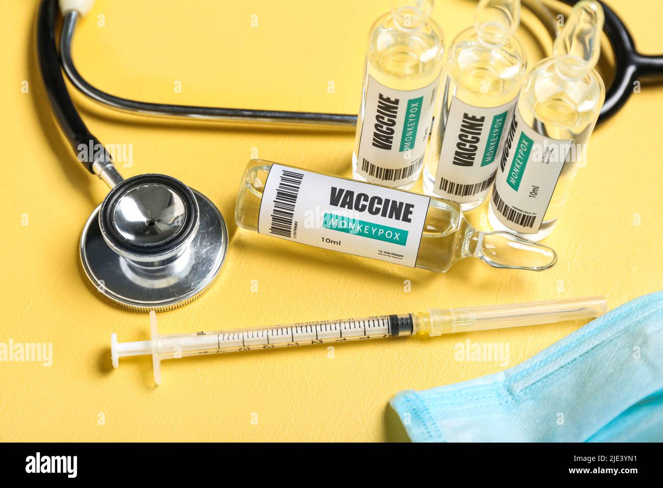 Ampules of monkeypox vaccine, syringe and stethoscope on yellow ...