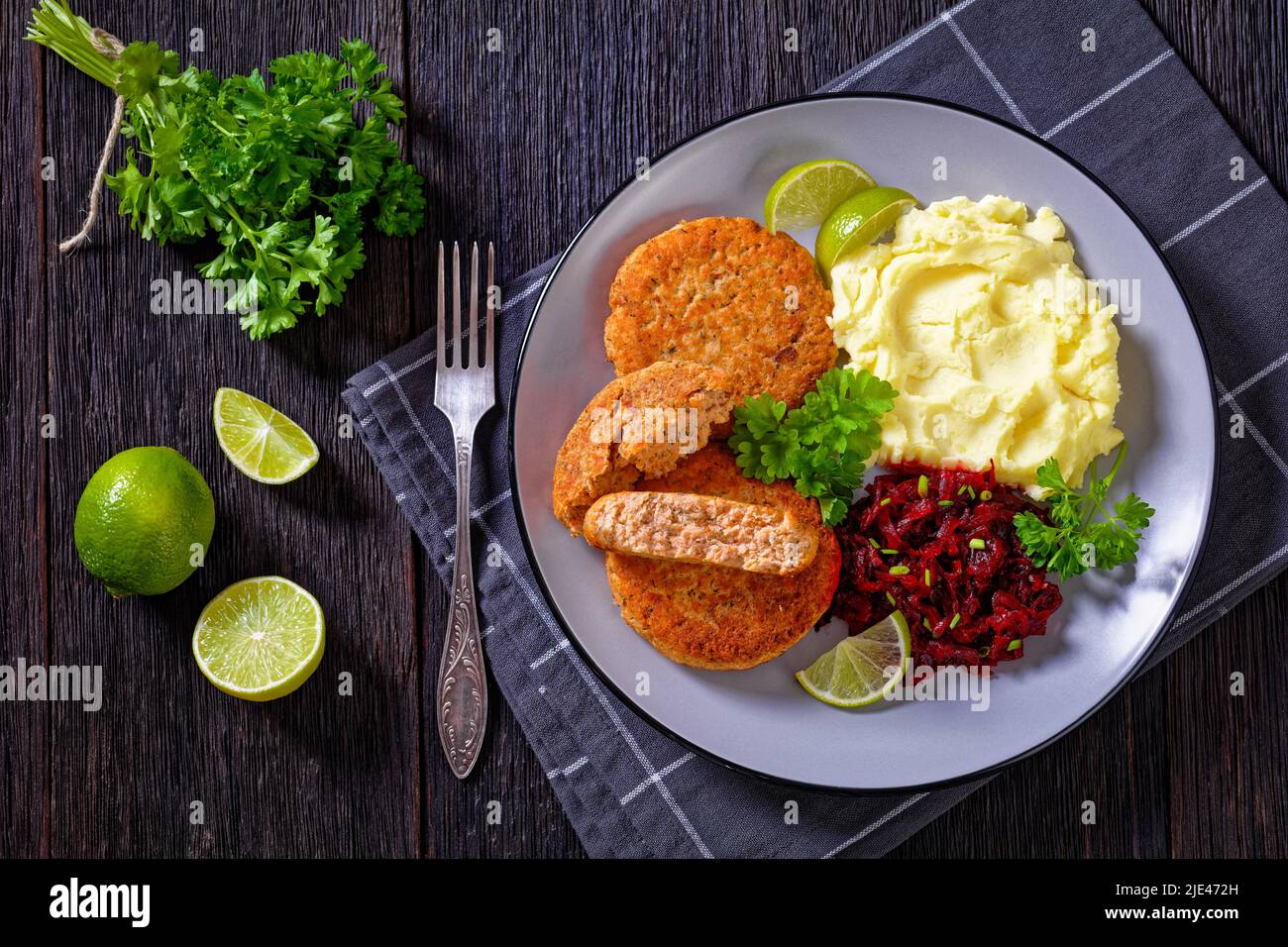 red fish patty with potato mash and beetroot salad on plate on dark ...