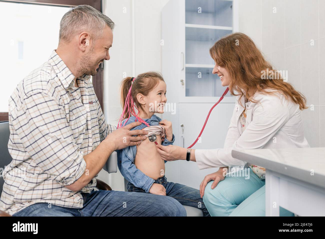 A young man shows his child to a doctor at a clinic appointment ...