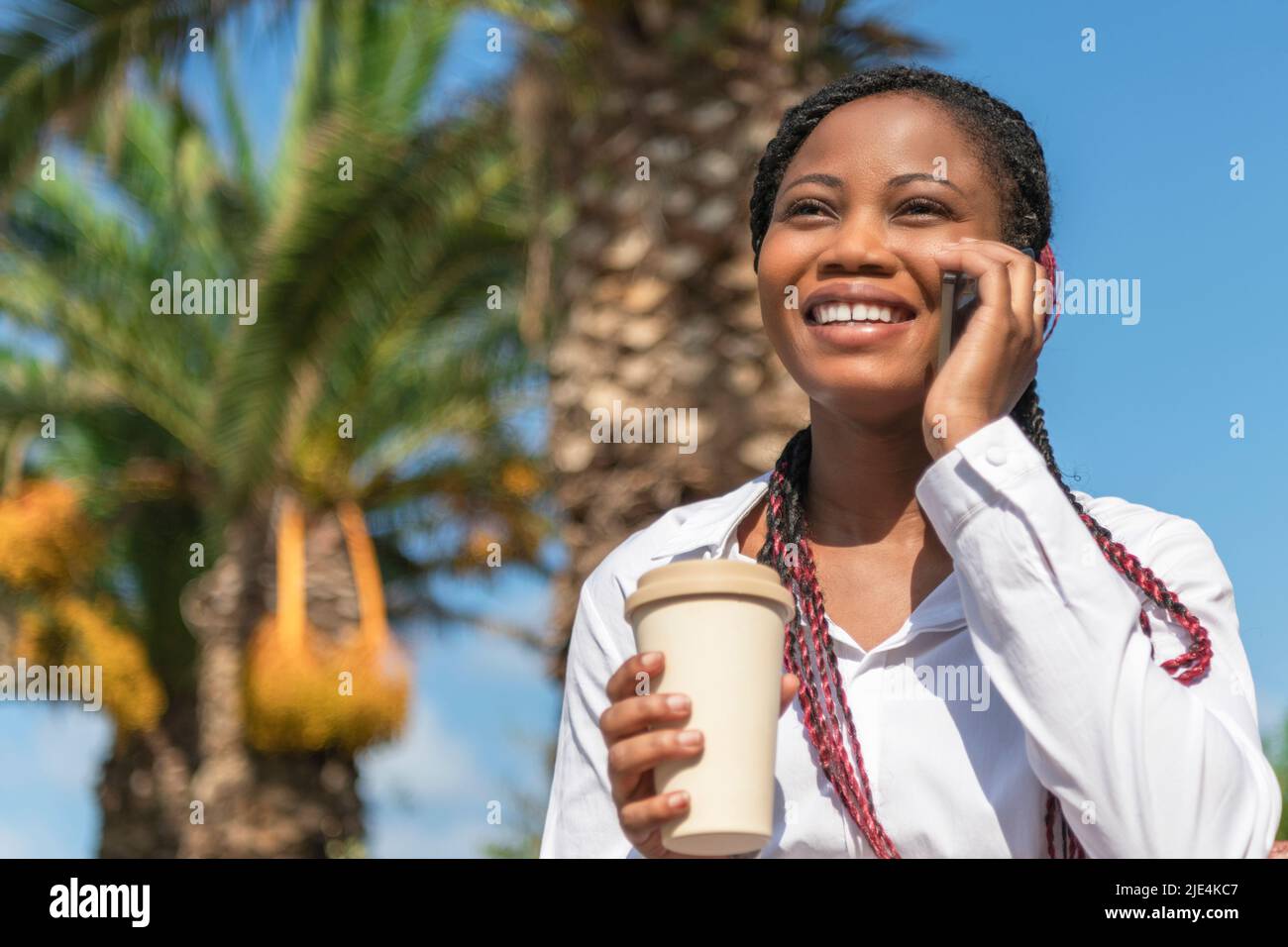 African woman with takeaway cup talking on her phone Stock Photo - Alamy