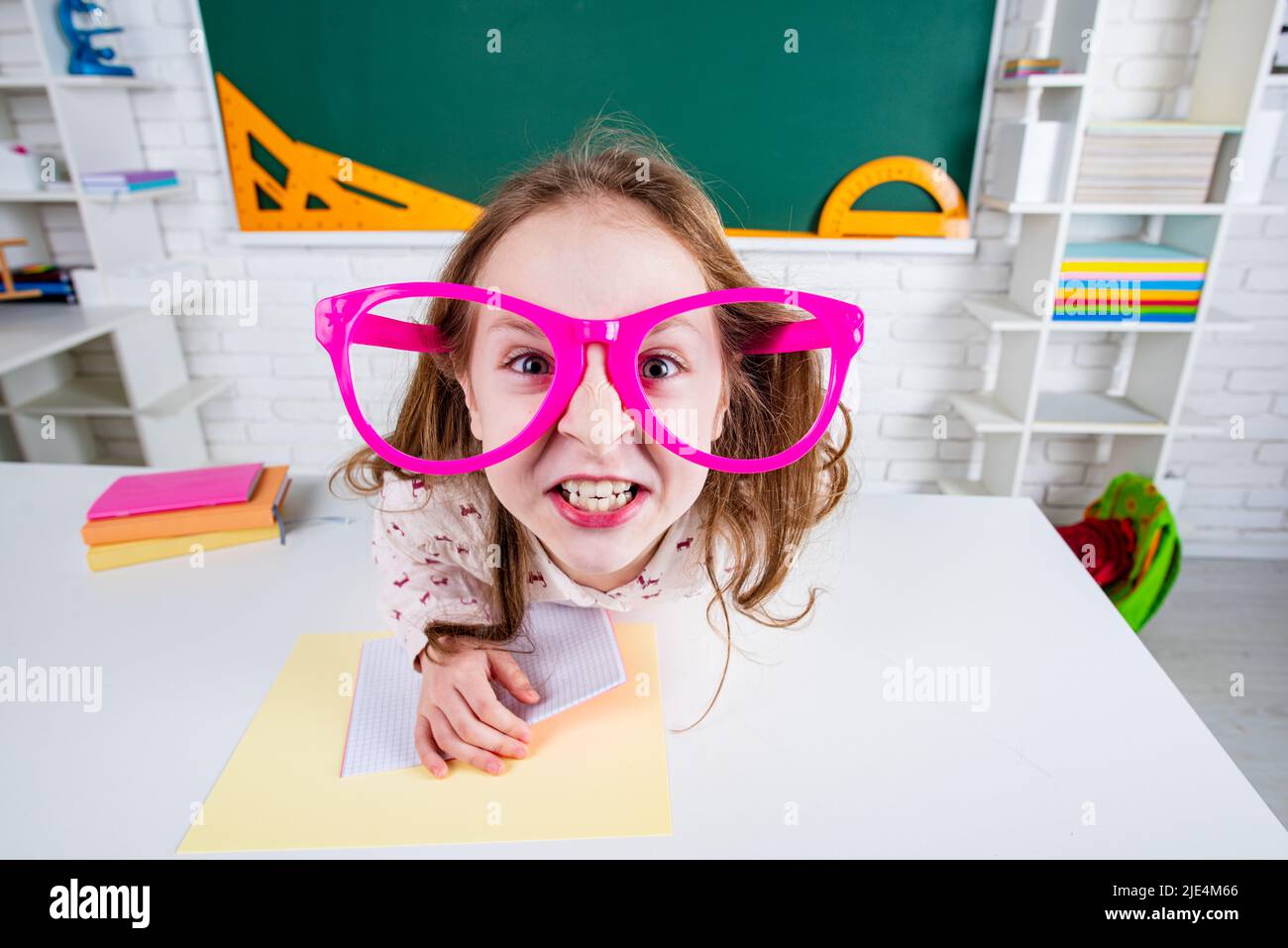 Funny angry child school girl with fun glasses in classroom. Crazy ...