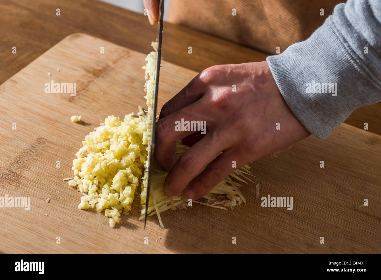 Chef hand at the end of the chopper on the cutting board cut ginger ...