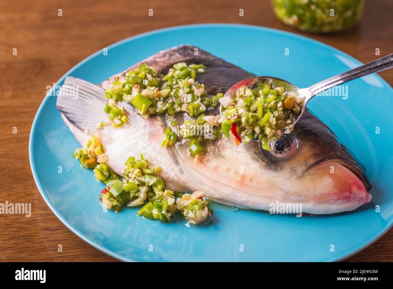 Covered with green chilli sauce fresh oxtail fish head by hand Stock ...