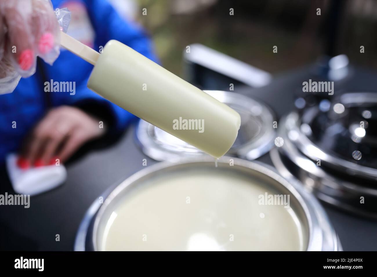 Person dipping ice cream in white chocolate in cafe Stock Photo - Alamy