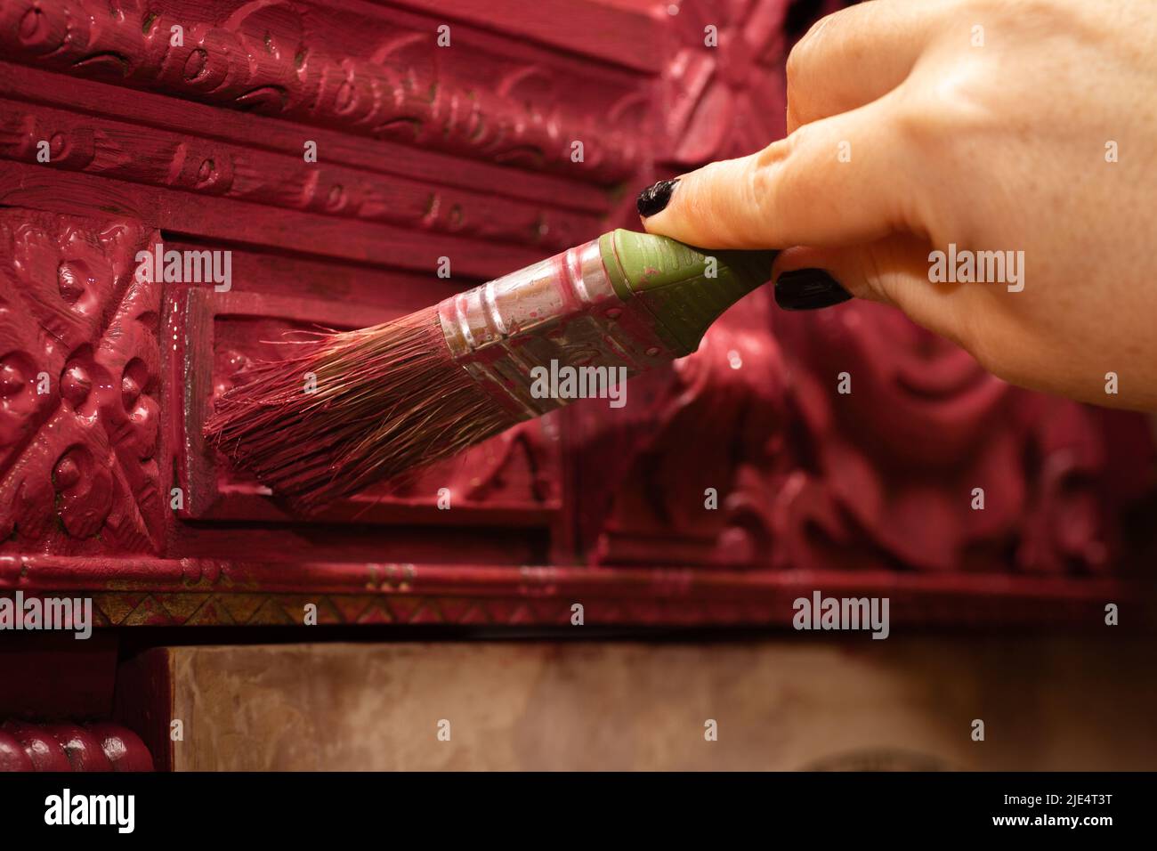 Paint brush in female hand carefully painting amazing wooden ornamented ...
