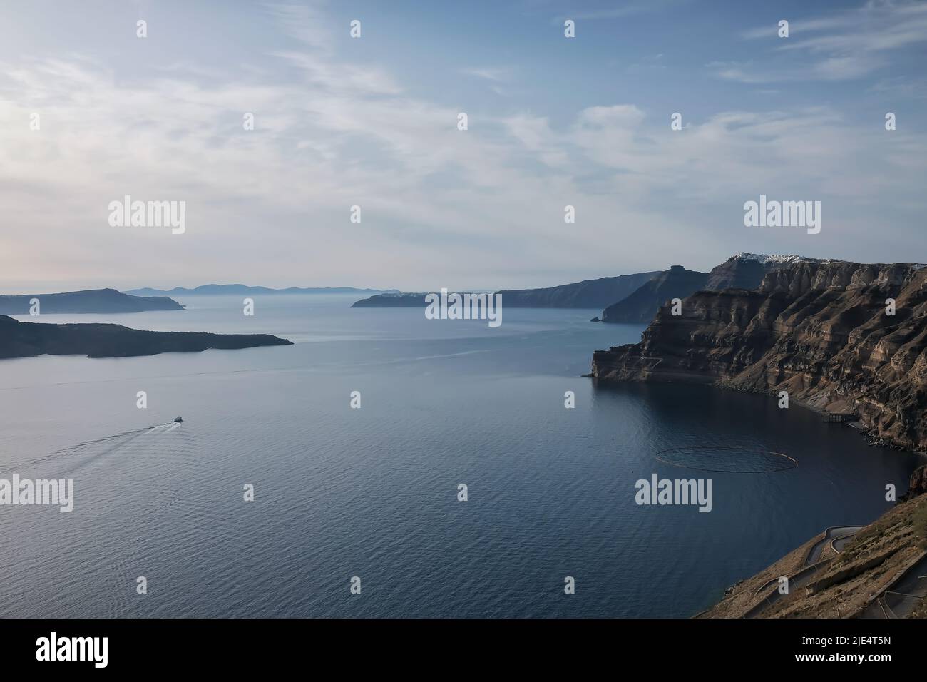 Breathtaking view of Fira, Oia, the volcano and a small boat leaving ...