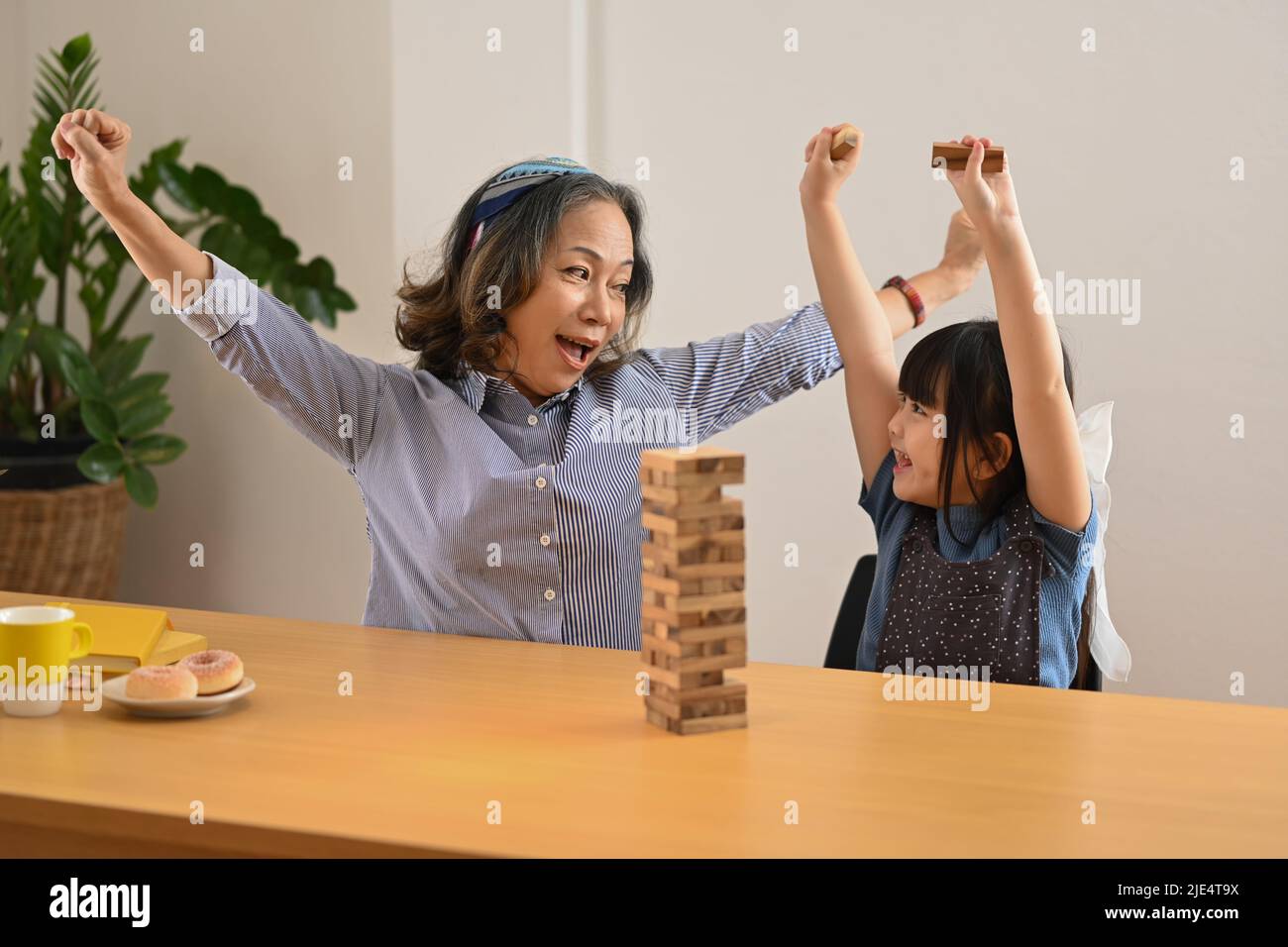 Joyful little asian child and middle aged grandma enjoy playing wood ...