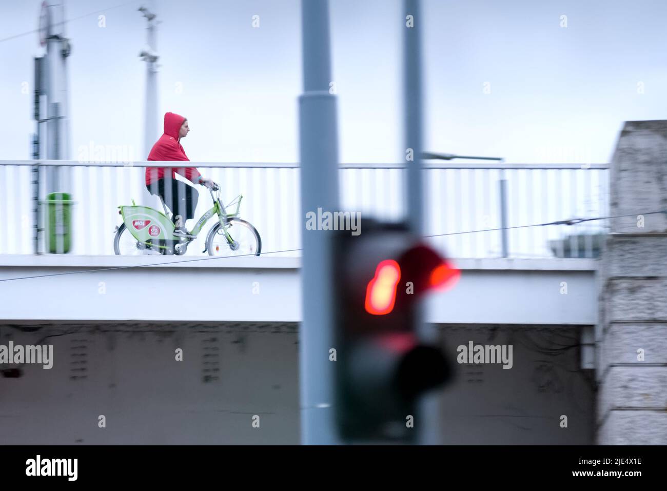 Person in the hood riding bicycle on a bridge Stock Photo - Alamy