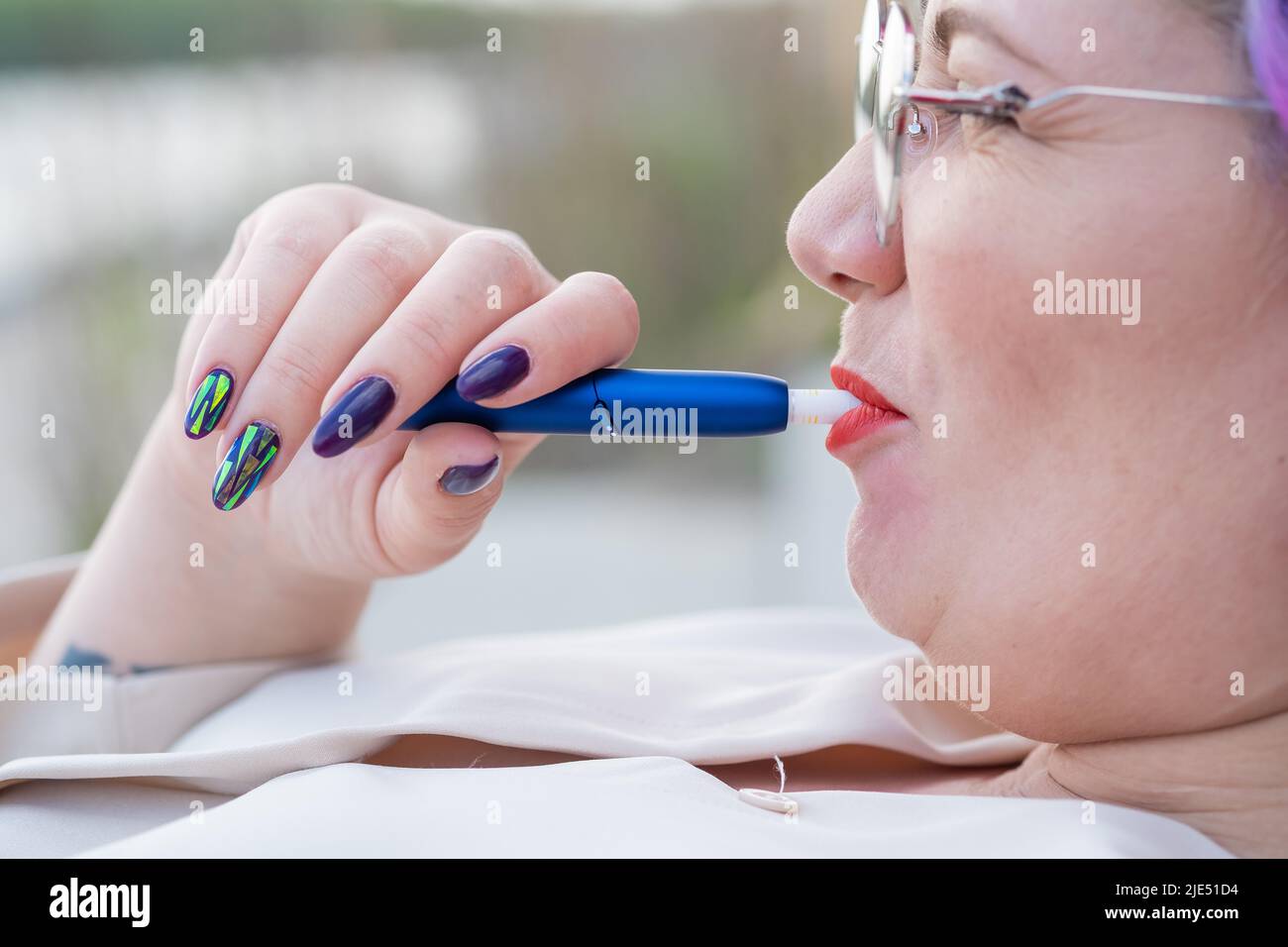 Caucasian woman with colored hair smokes an electronic cigarette Stock ...