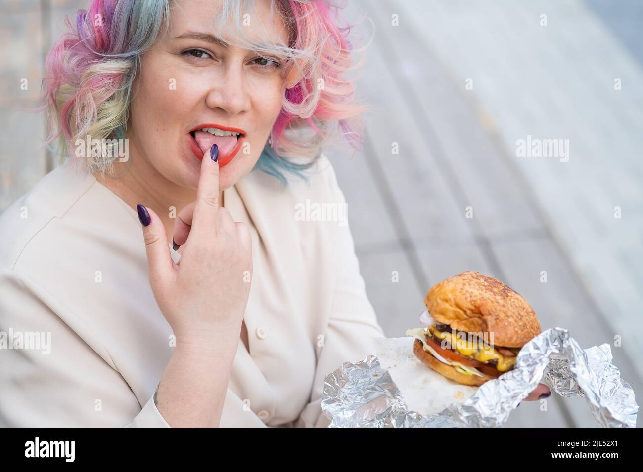 Caucasian woman with curly colored hair eating burger. Bad eating ...