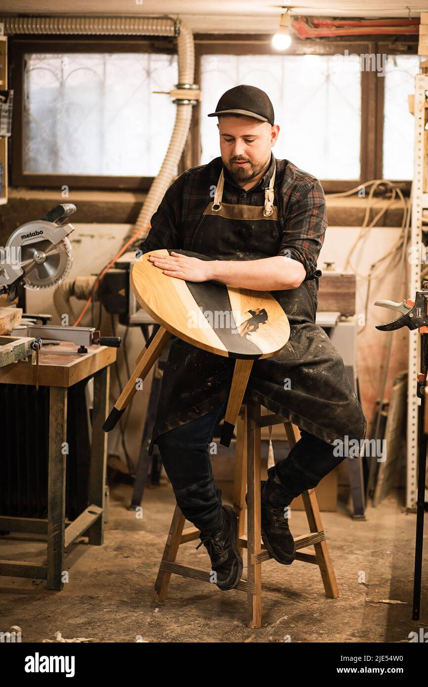 Vertical shot of confident bearded carpenter in woodworking process ...