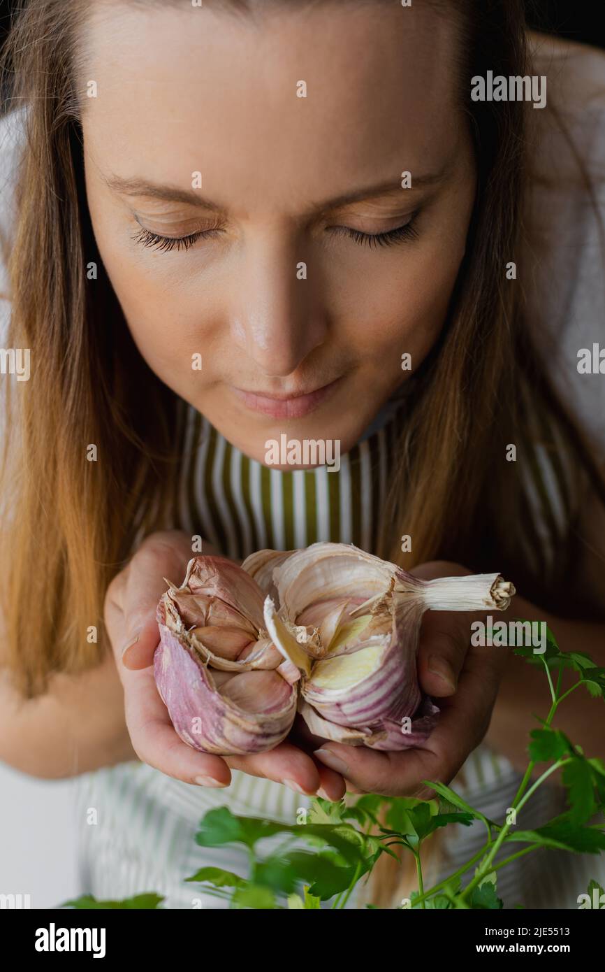 Vertical closeup woman face with close eyes holding and smelling garlic ...
