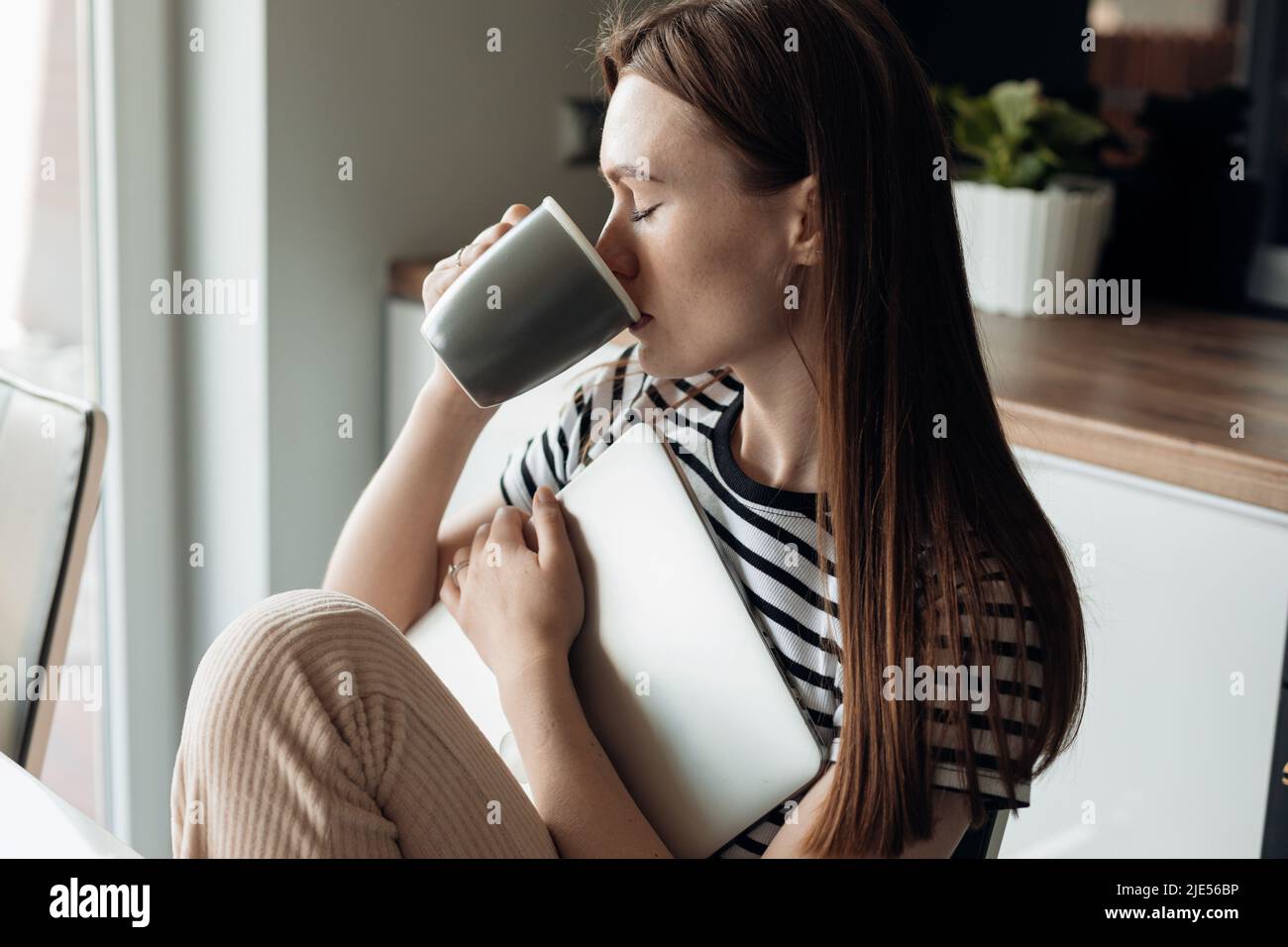 Portrait of beautiful young woman drinking and taking sips of morning ...