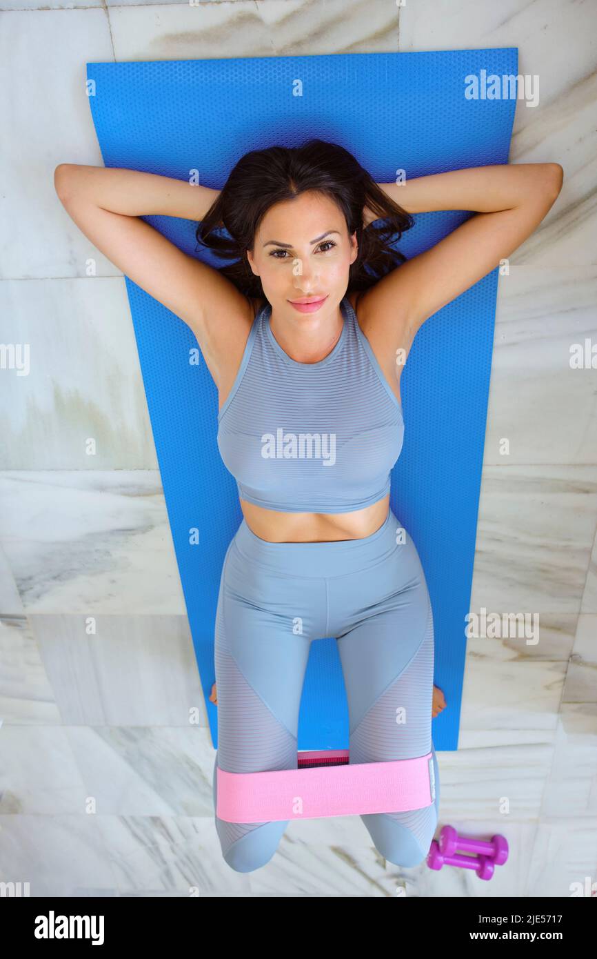 young woman doing sports at home on wooden trunk with resistance band ...