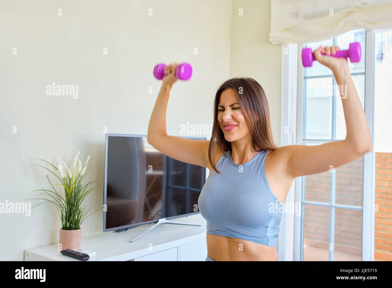 young woman doing sports at home on wooden trunk with resistance band ...