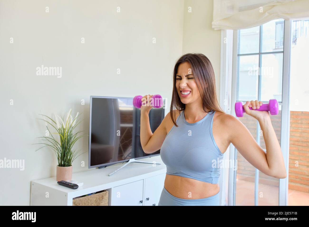 young woman doing sports at home on wooden trunk with resistance band ...
