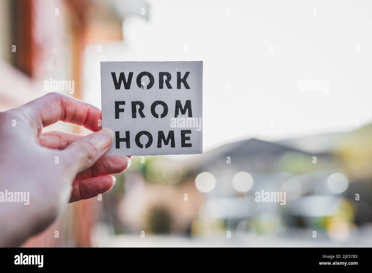 work from home sign being hold in front of out of focus backyard with ...