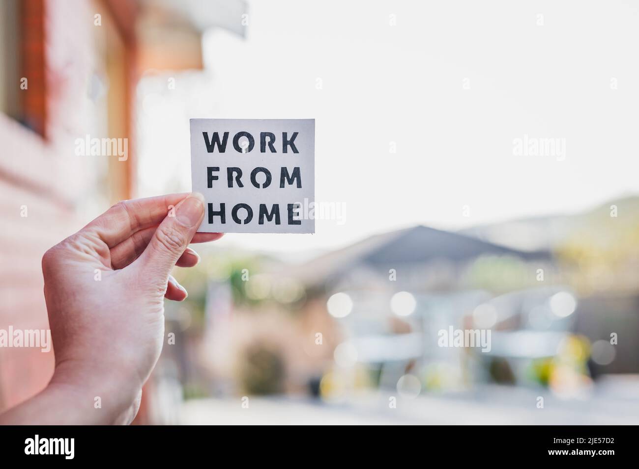 work from home sign being hold in front of out of focus backyard with ...