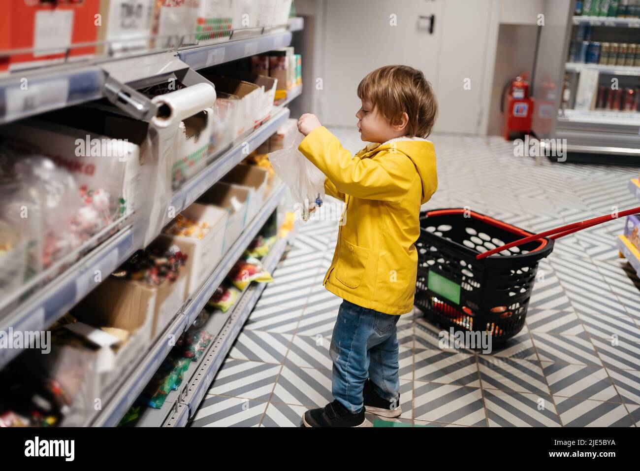 child in the market with a grocery cart, puts sweets in a bag Stock ...
