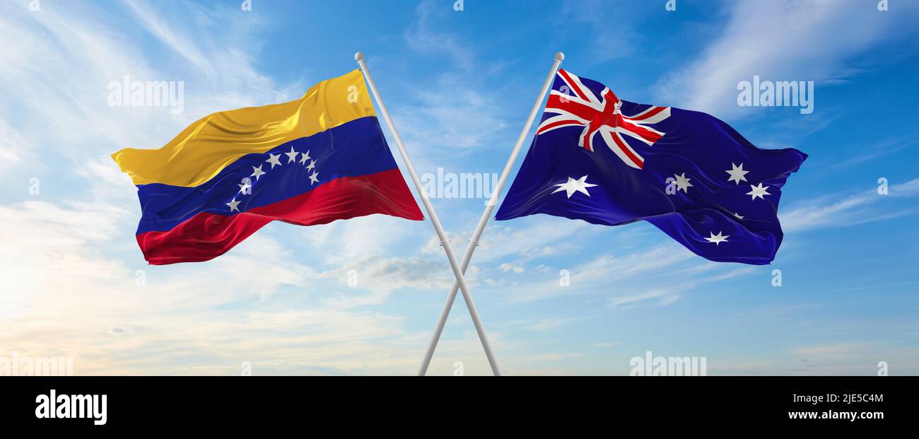 two crossed flags Venezuela and Australia waving in wind at cloudy sky ...