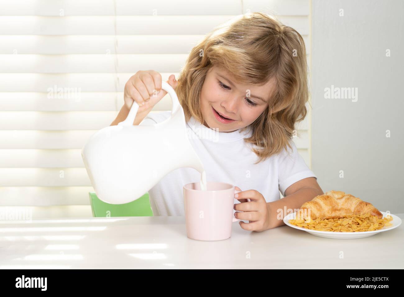 School chil pouring whole cows milk for breakfast. Funny kid boy having ...