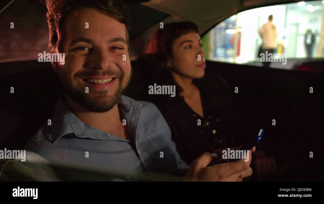 Happy man in car backseat at night after work portrait smiling holding ...
