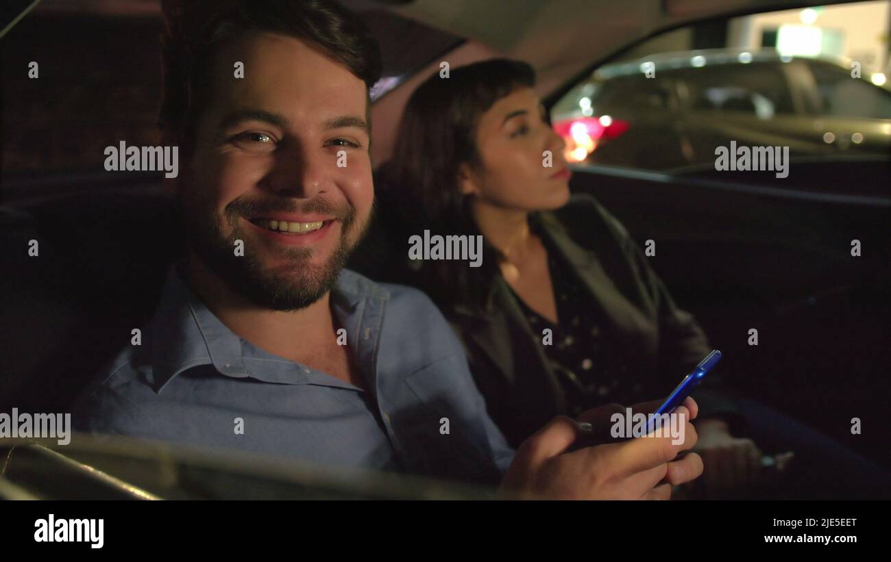 Young man riding taxi holding smartphone device. Person turning head to ...