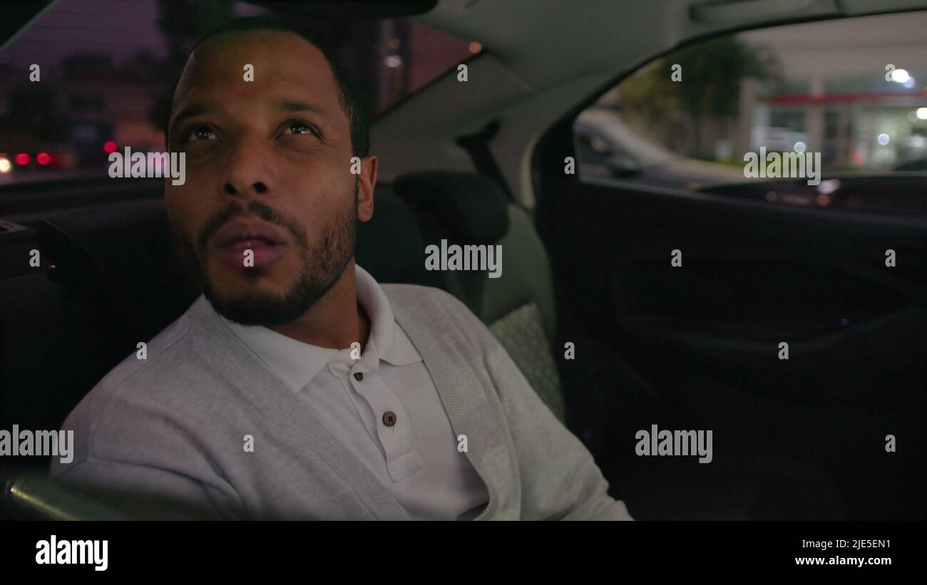 One Young Black Man Sitting In Car Backseat At Night Looking Out