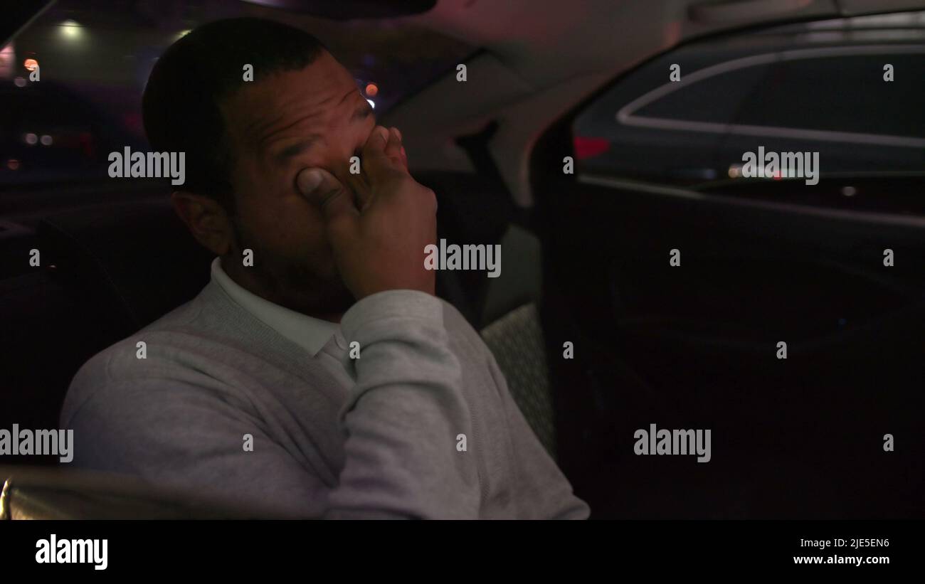 One stressed black man sitting in car backseat stuck in traffic ...