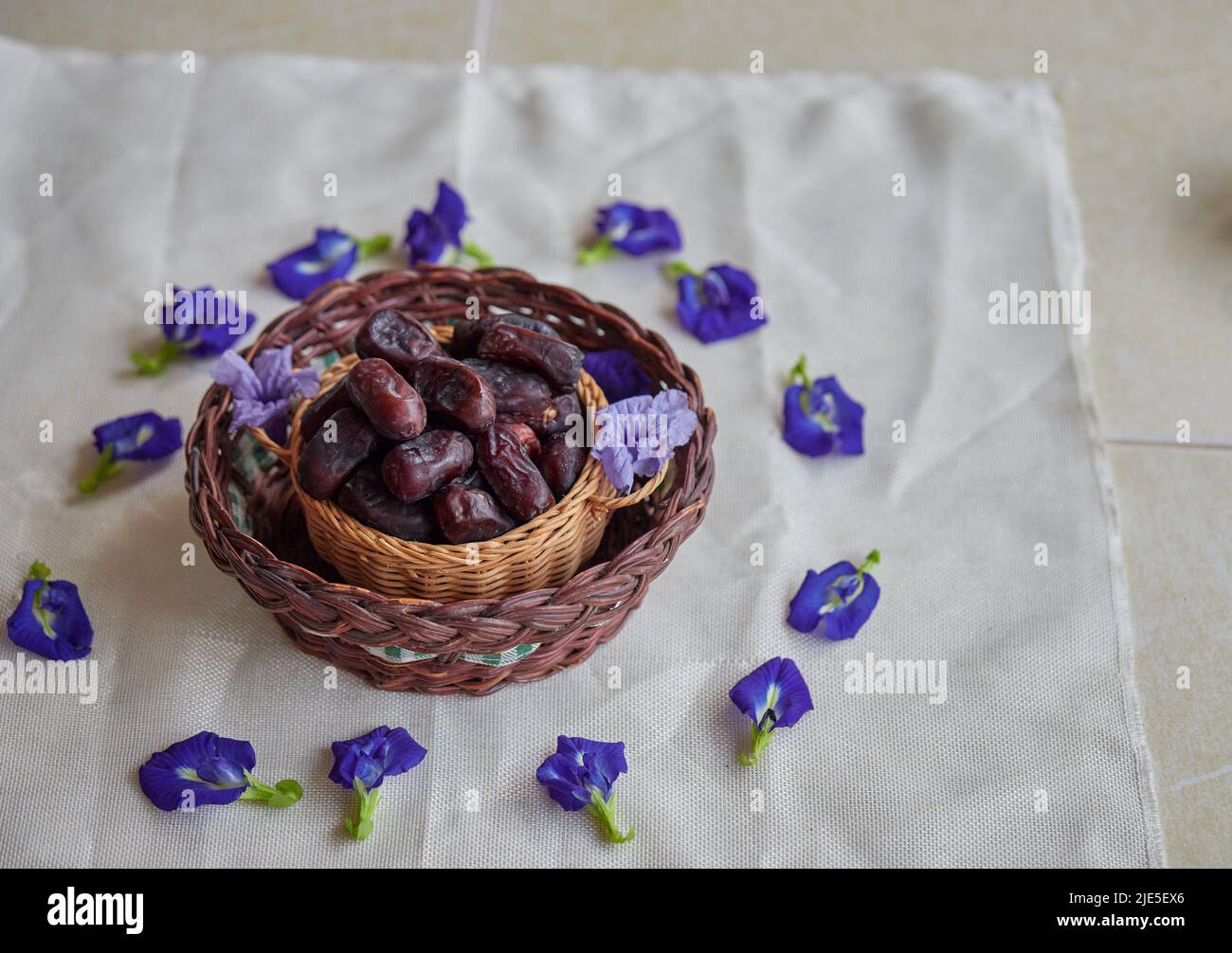 Dried dates in wicker basket with butterfly pea flower decoration Stock ...