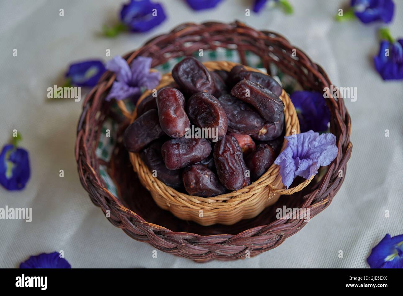 Dried dates in wicker basket with butterfly pea flower decoration Stock ...