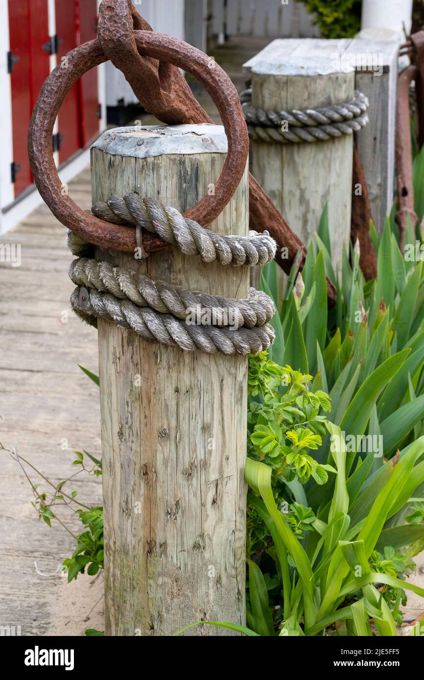 Wooden post with rusted iron rings on top and fishing rope wrapped ...