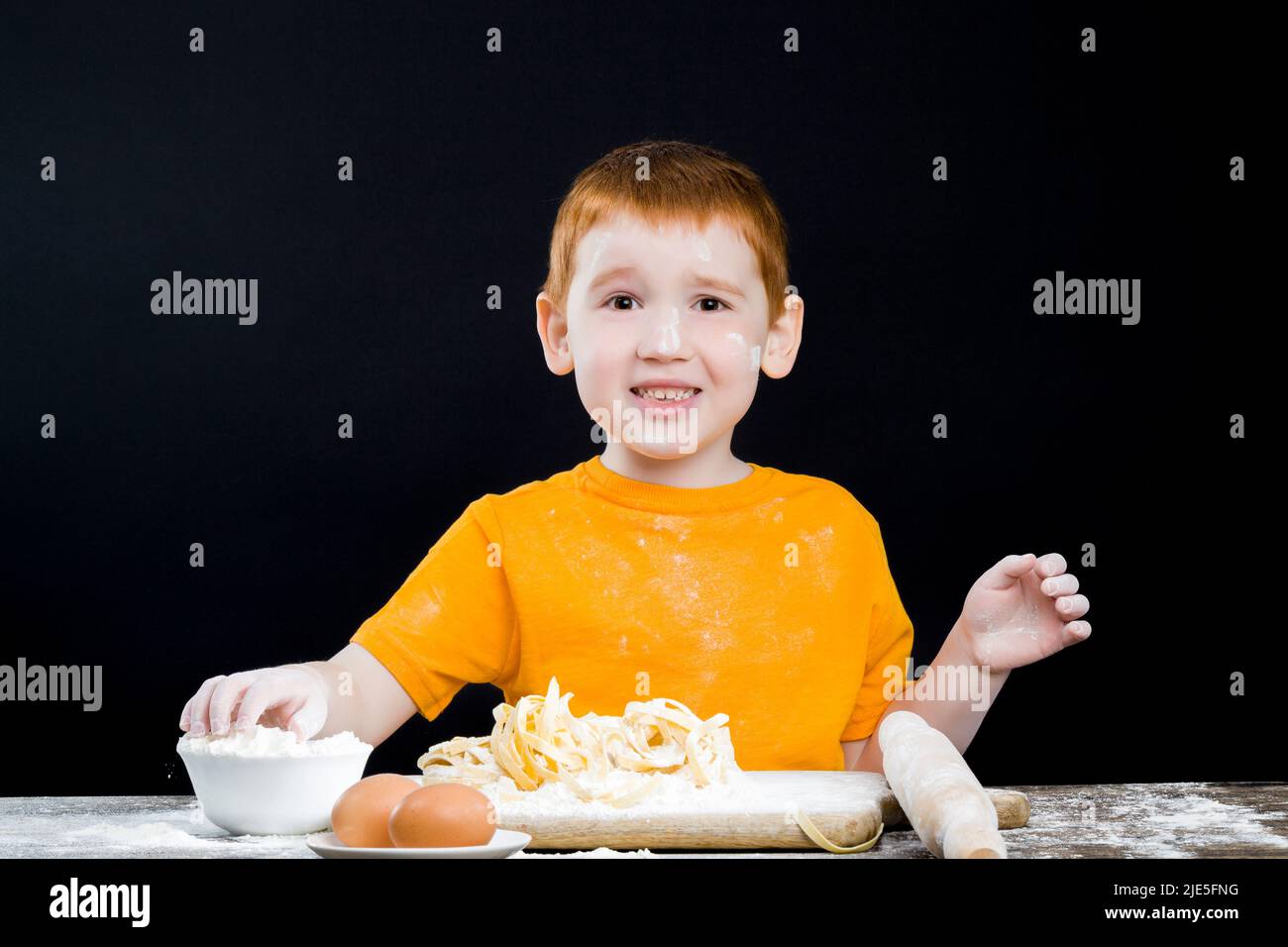 baby boy in the kitchen while helping with cooking, boy with red hair ...