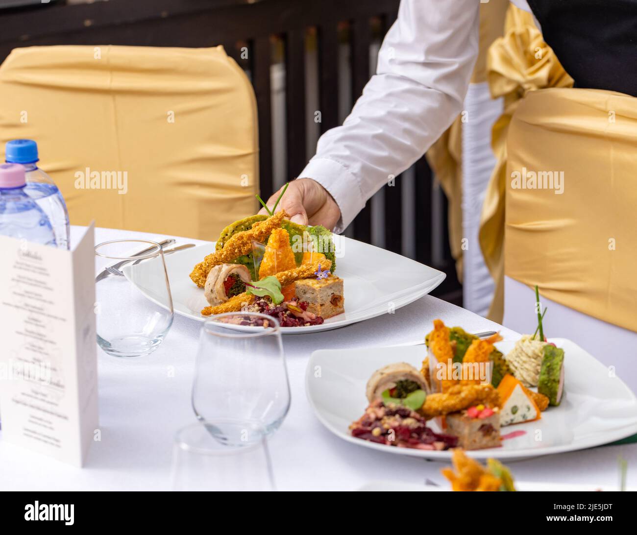 Restaurant waitress serving table with starter dishes. Wedding table ...