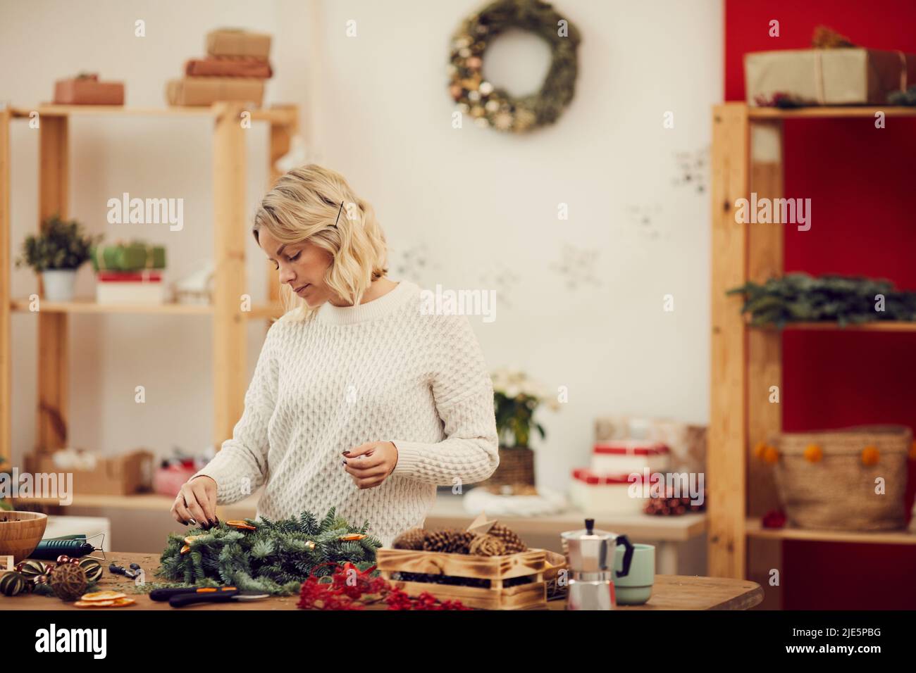 Young woman in white sweater standing at table and working with natural ...