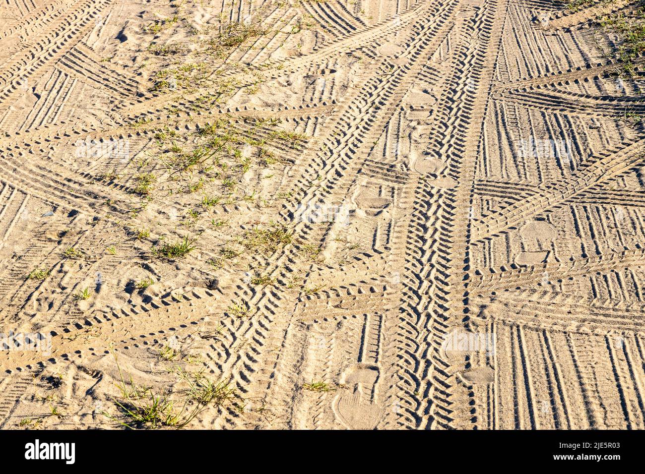 car traces and footprints on surface of sand country road in summer ...