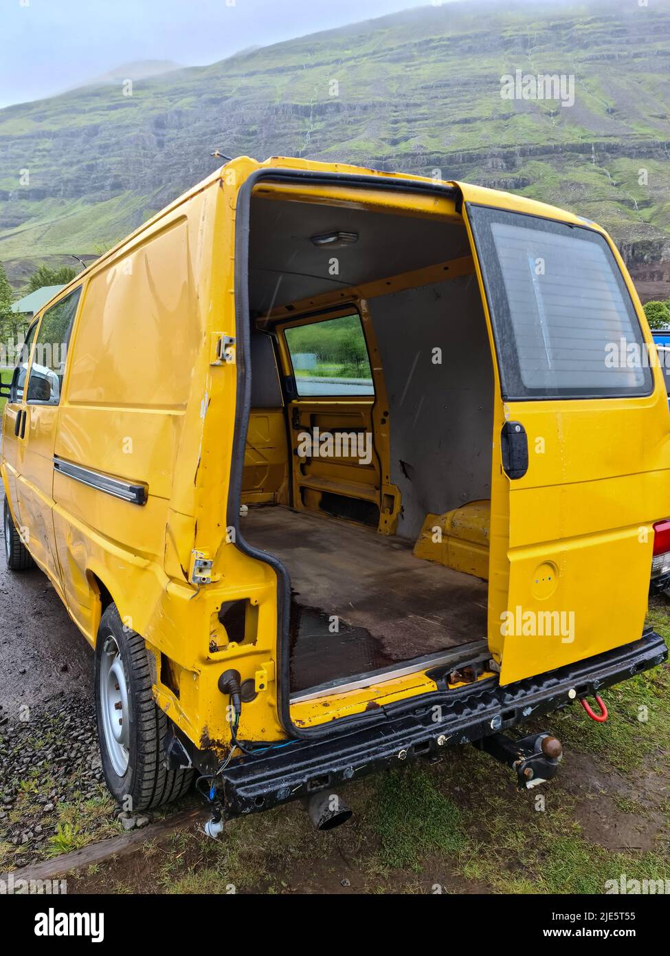 A yellow abandoned transporter car with a missing door in the back ...