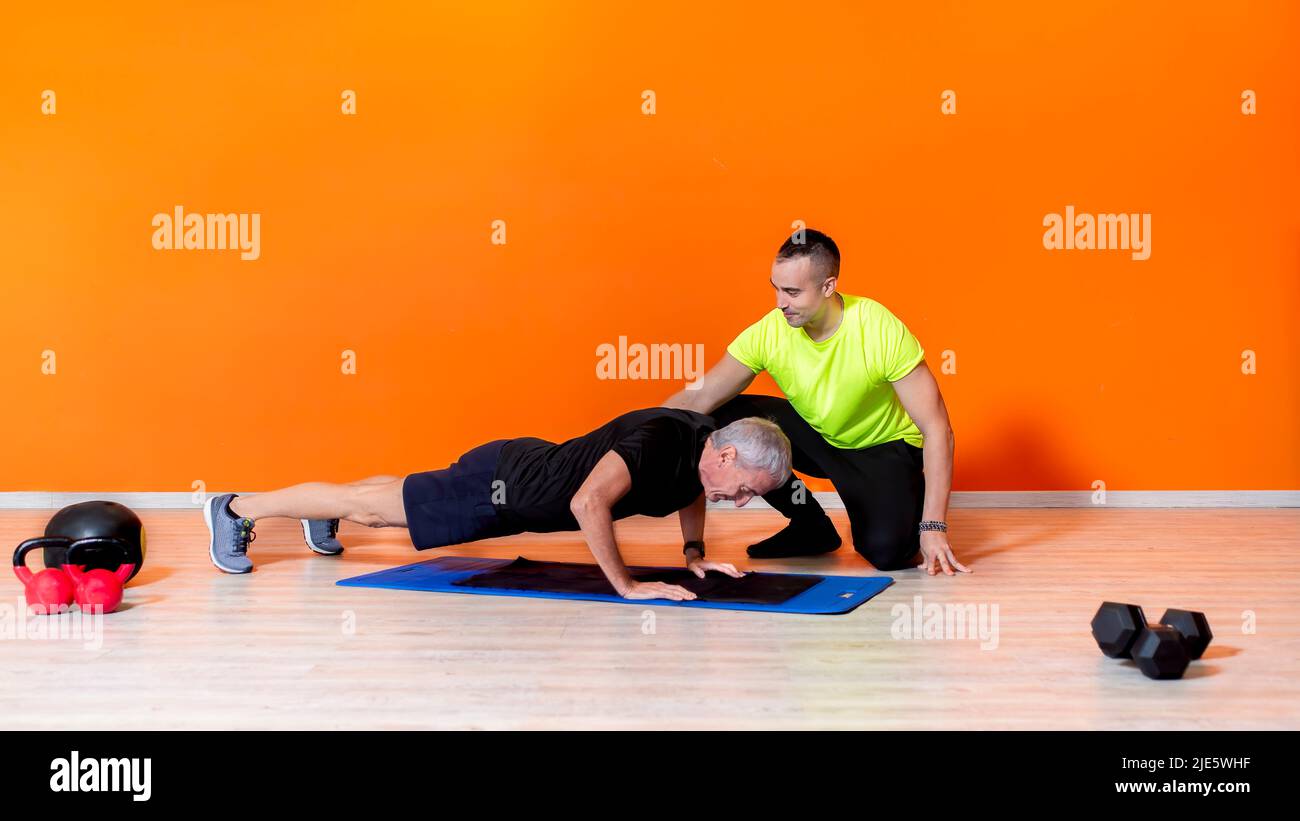 focused senior fit man doing push up workout exercise laying at the gym ...