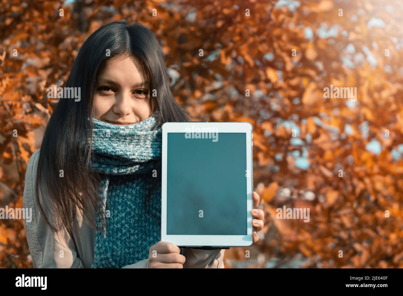 Girl shows the screen of the tablet to the viewer while standing ...