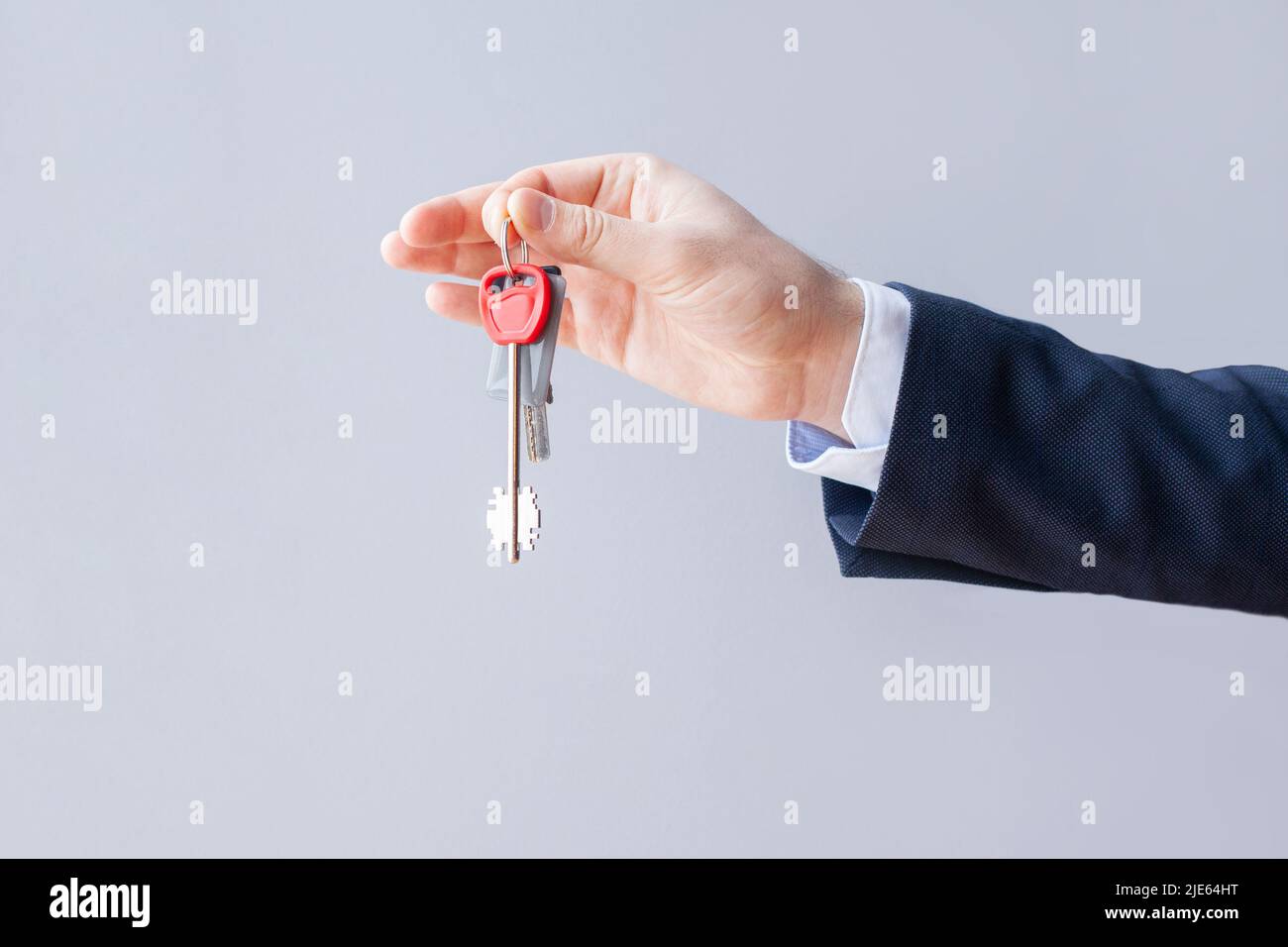 Businessman hand holding house keys on white background Stock Photo - Alamy