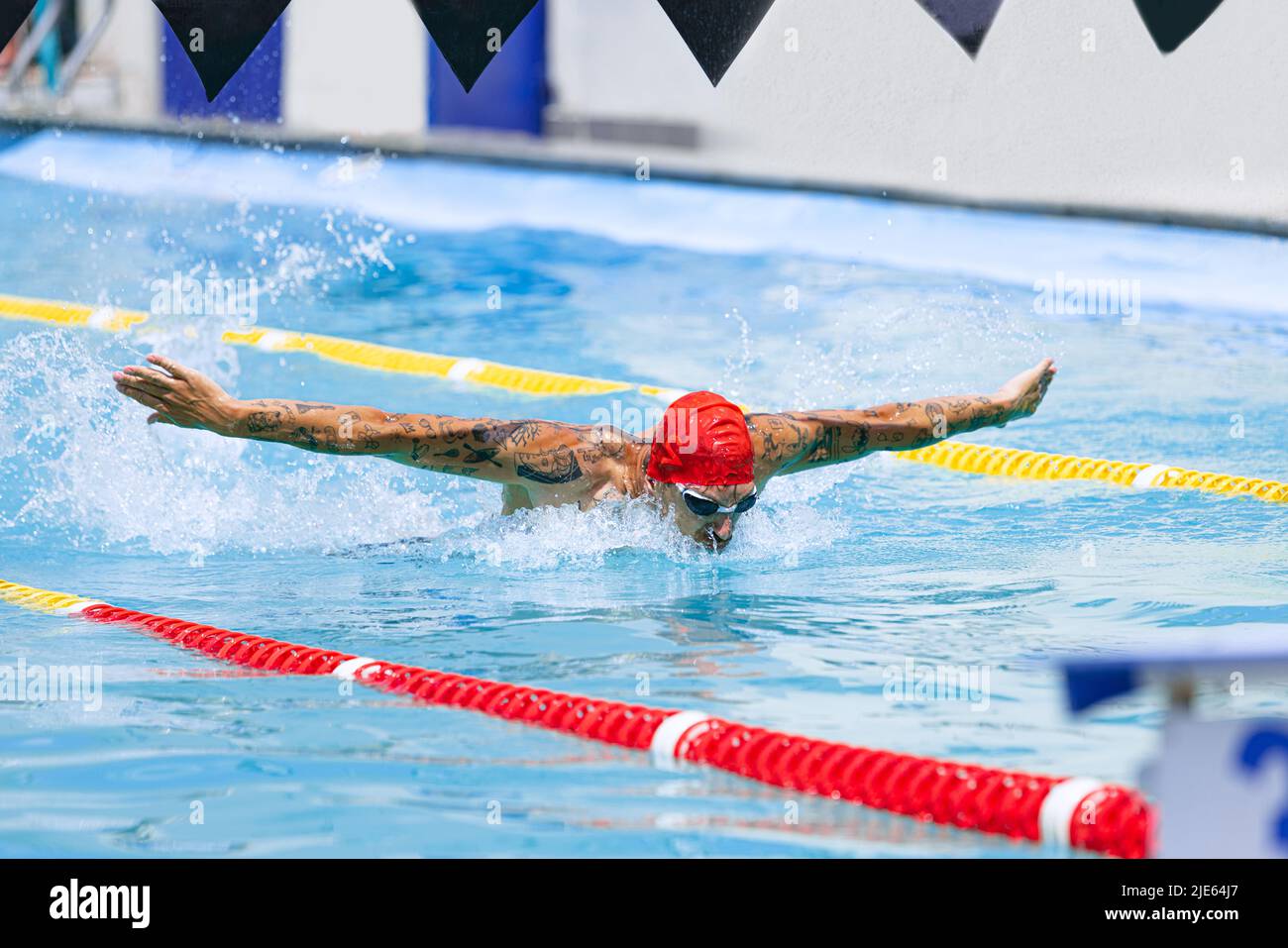 Young muscular man, professional swimmer in goggles training at public ...