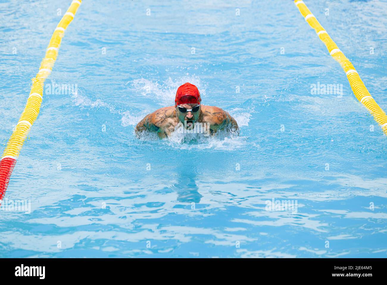 One athlete, male professional swimmer in goggles and red swimming cap ...