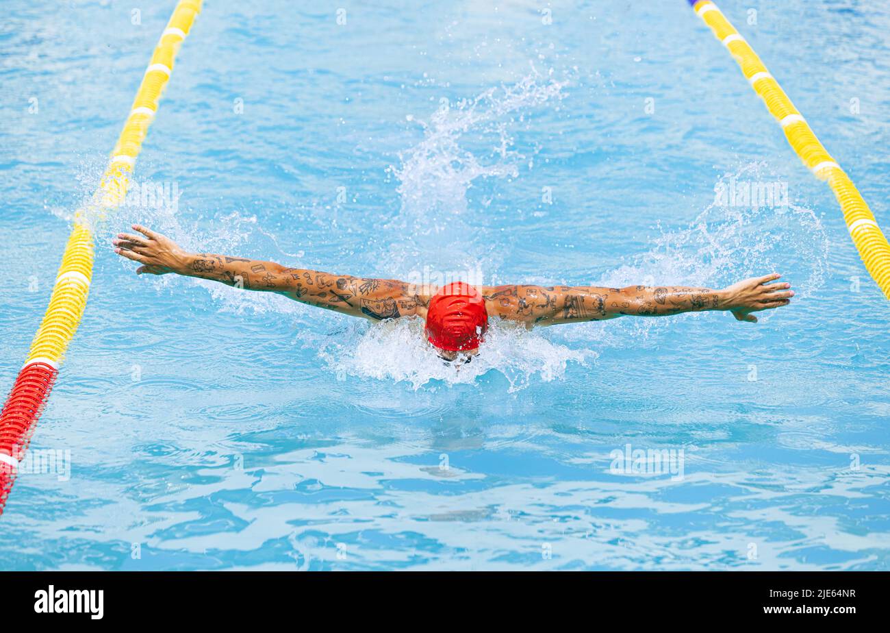 Young muscular man, professional swimmer in goggles training at public ...