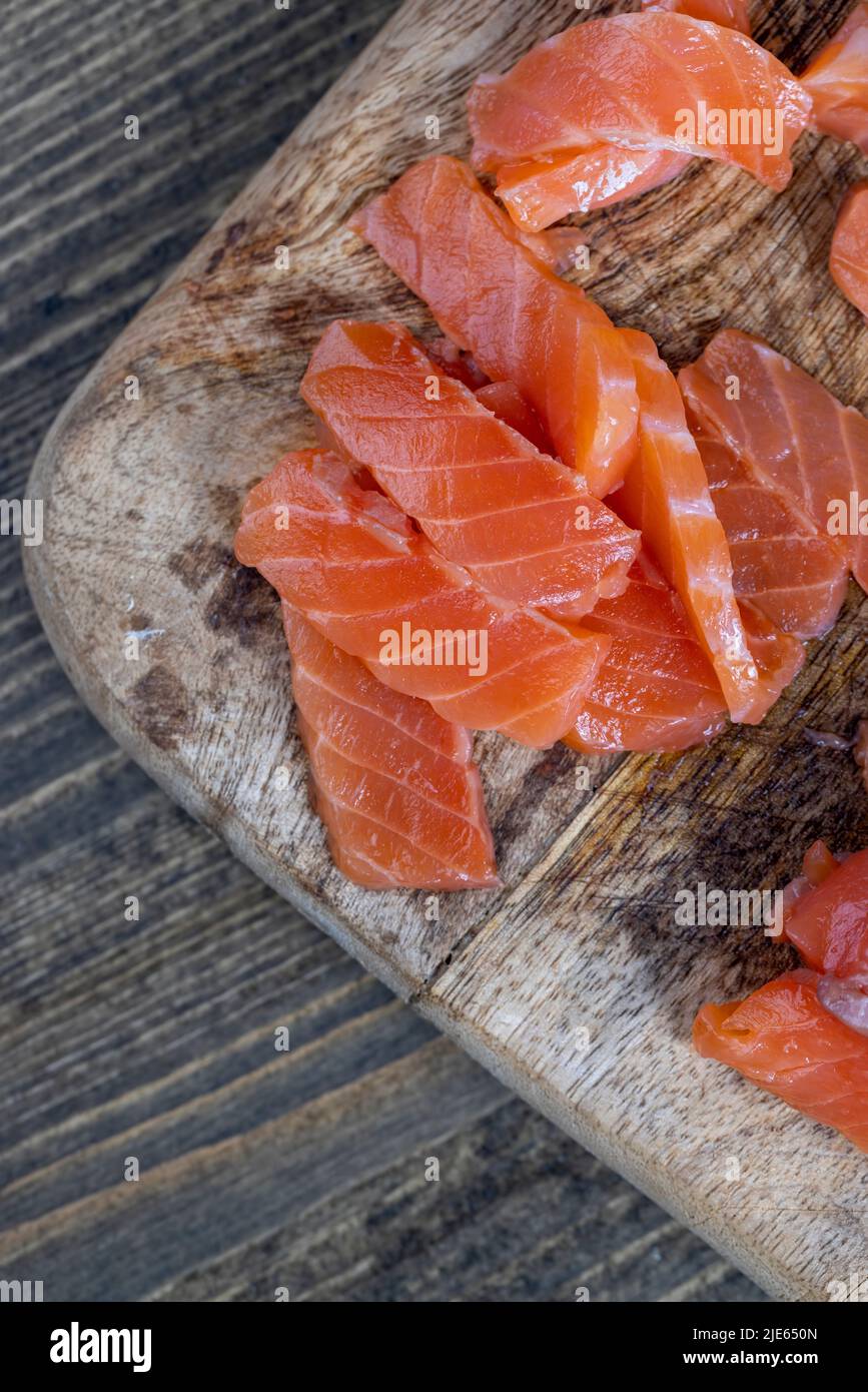 sliced red salted salmon during cooking, cutting fish fillets during ...