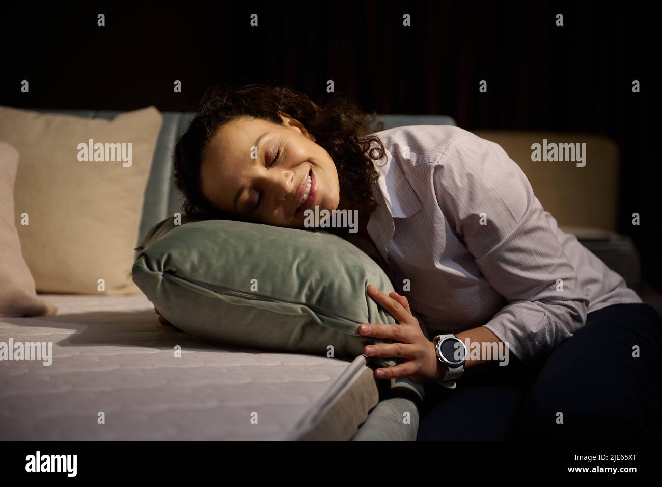 Relaxed woman smiles toothy smile, resting her head on green veloUr ...