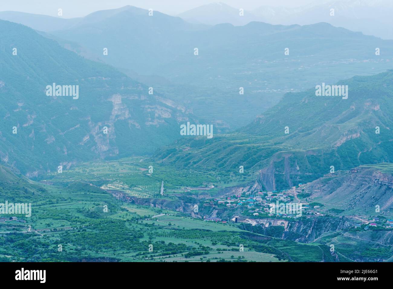 foggy alpine valley with settlements and fields between mountain peaks ...