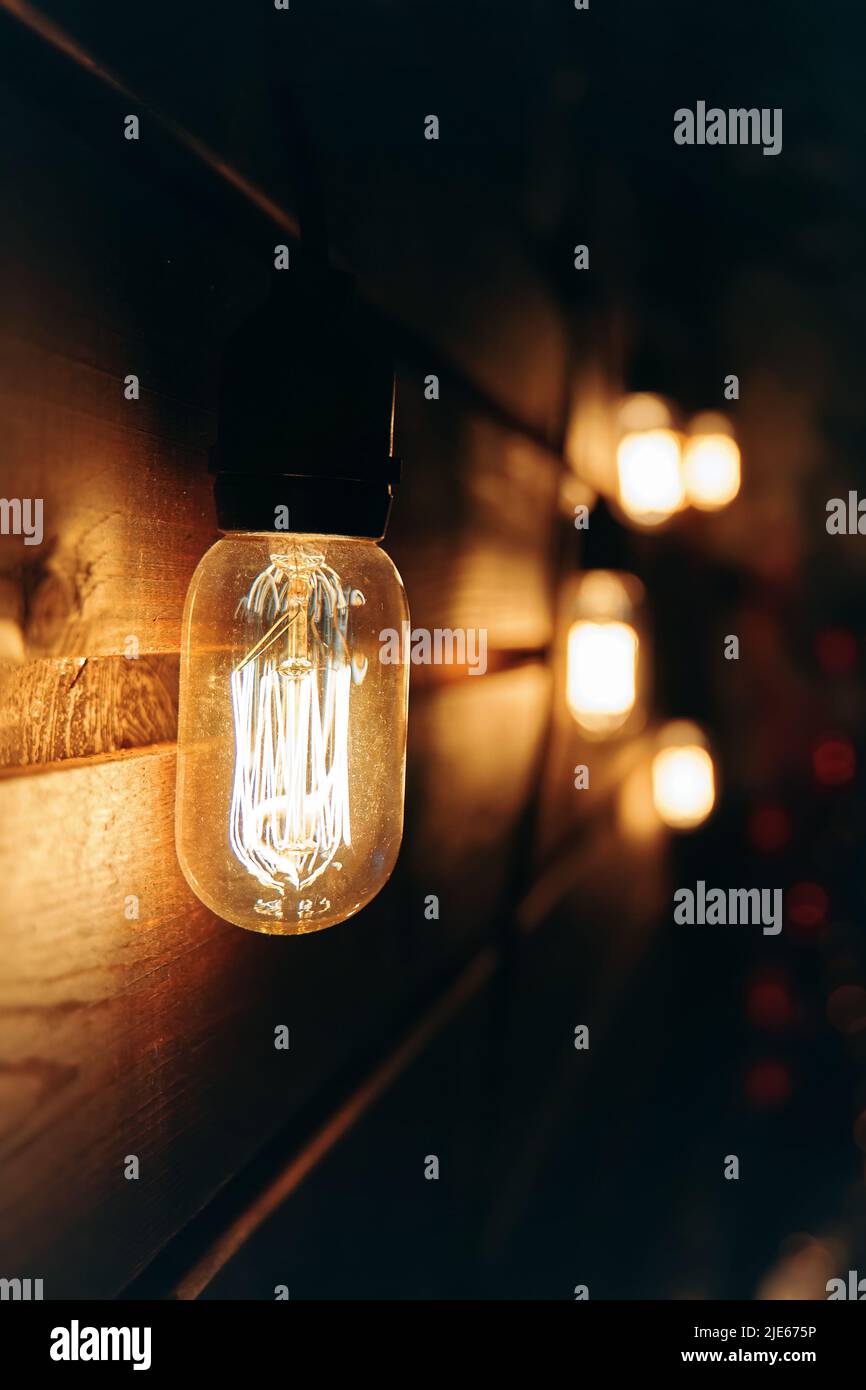 Incandescent Edison type bulb on wooden wall Stock Photo - Alamy